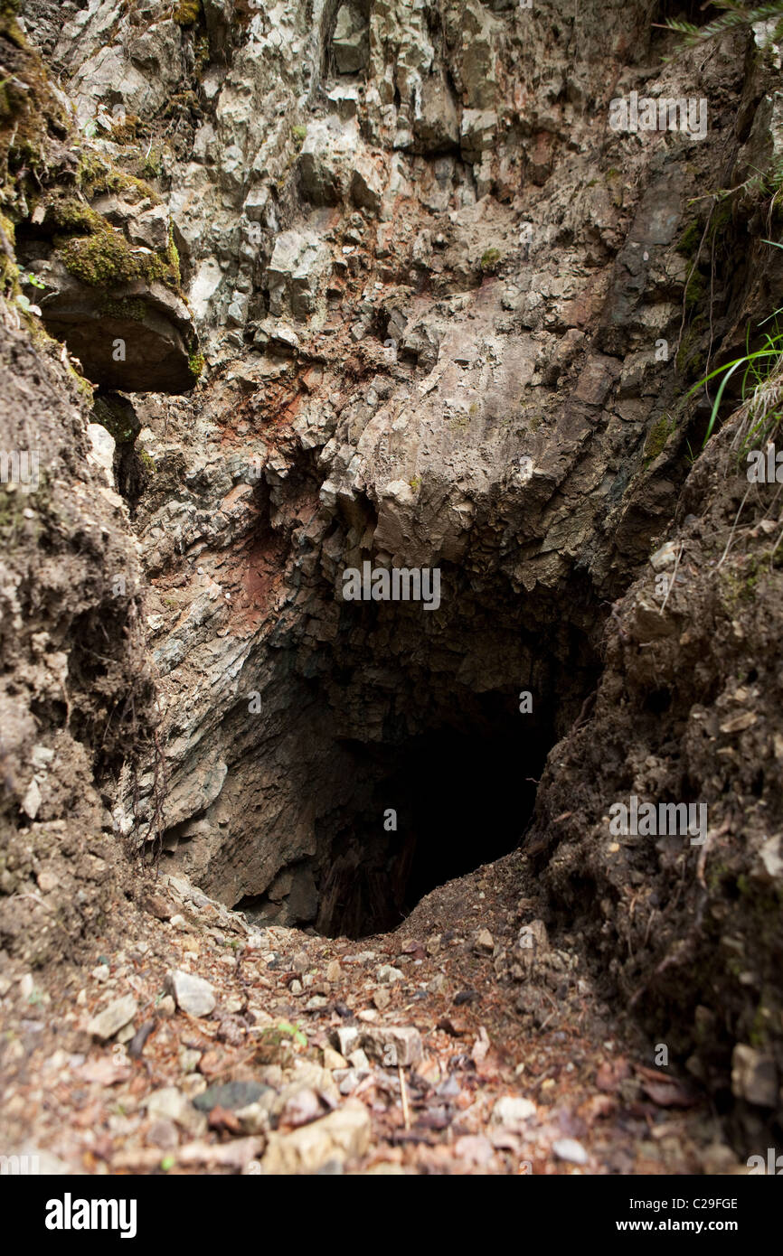 A mysterious rock cave in the side of a hill Stock Photo - Alamy