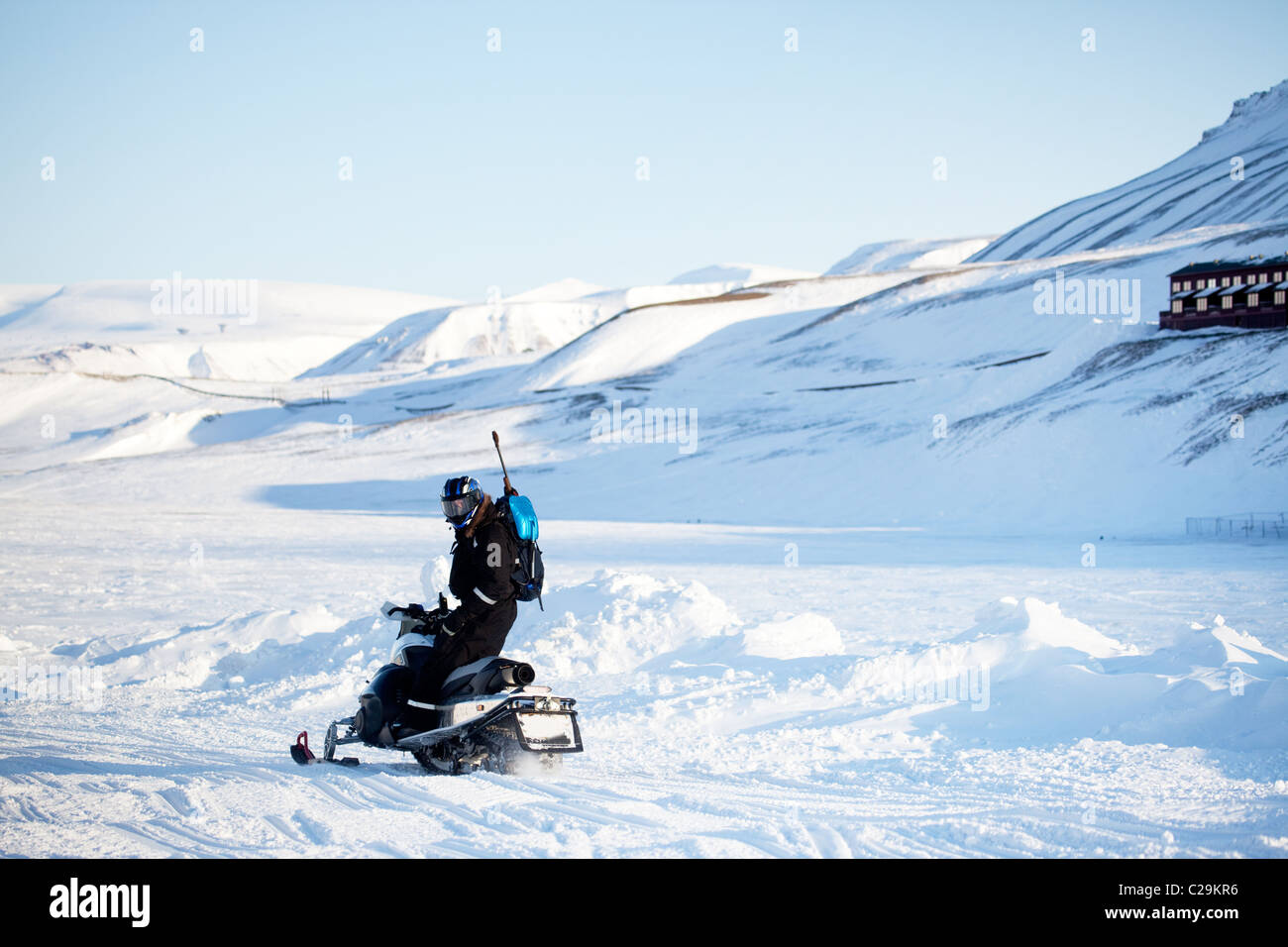 A man on a snowmobile with a gun and shovel for safety Stock Photo - Alamy