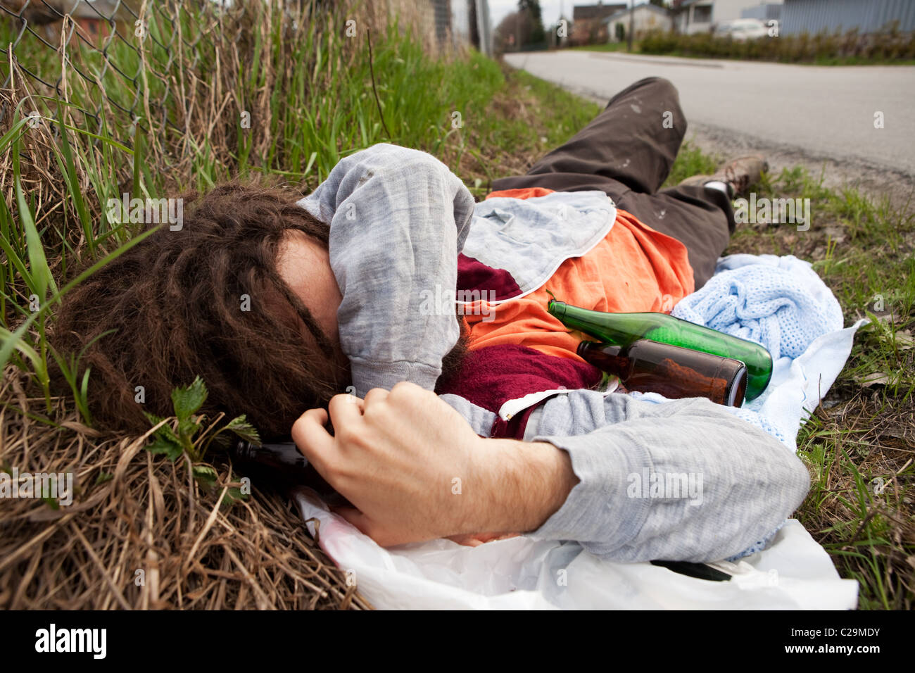A homeless drunk person laying by the edge of the road Stock Photo - Alamy