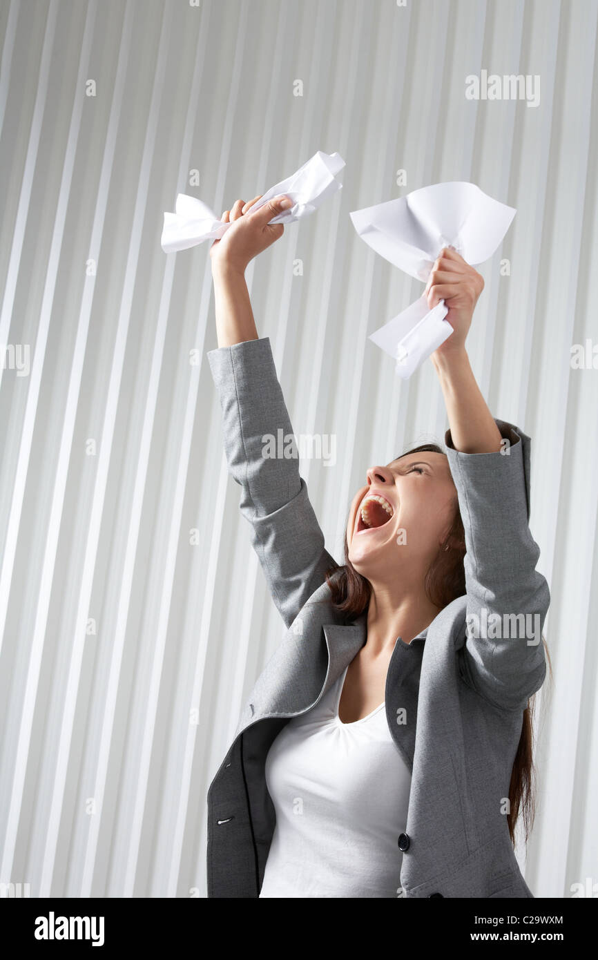 A depressed woman raising her hands with crumpled paper and screaming ...