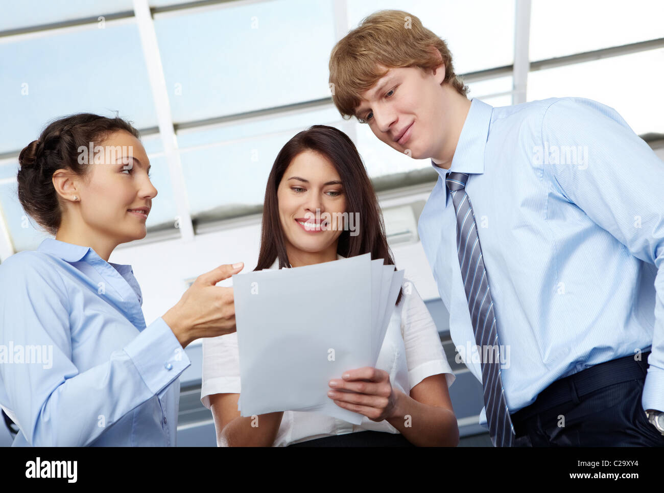 Portrait of confident businesswoman explaining project to co-workers at ...