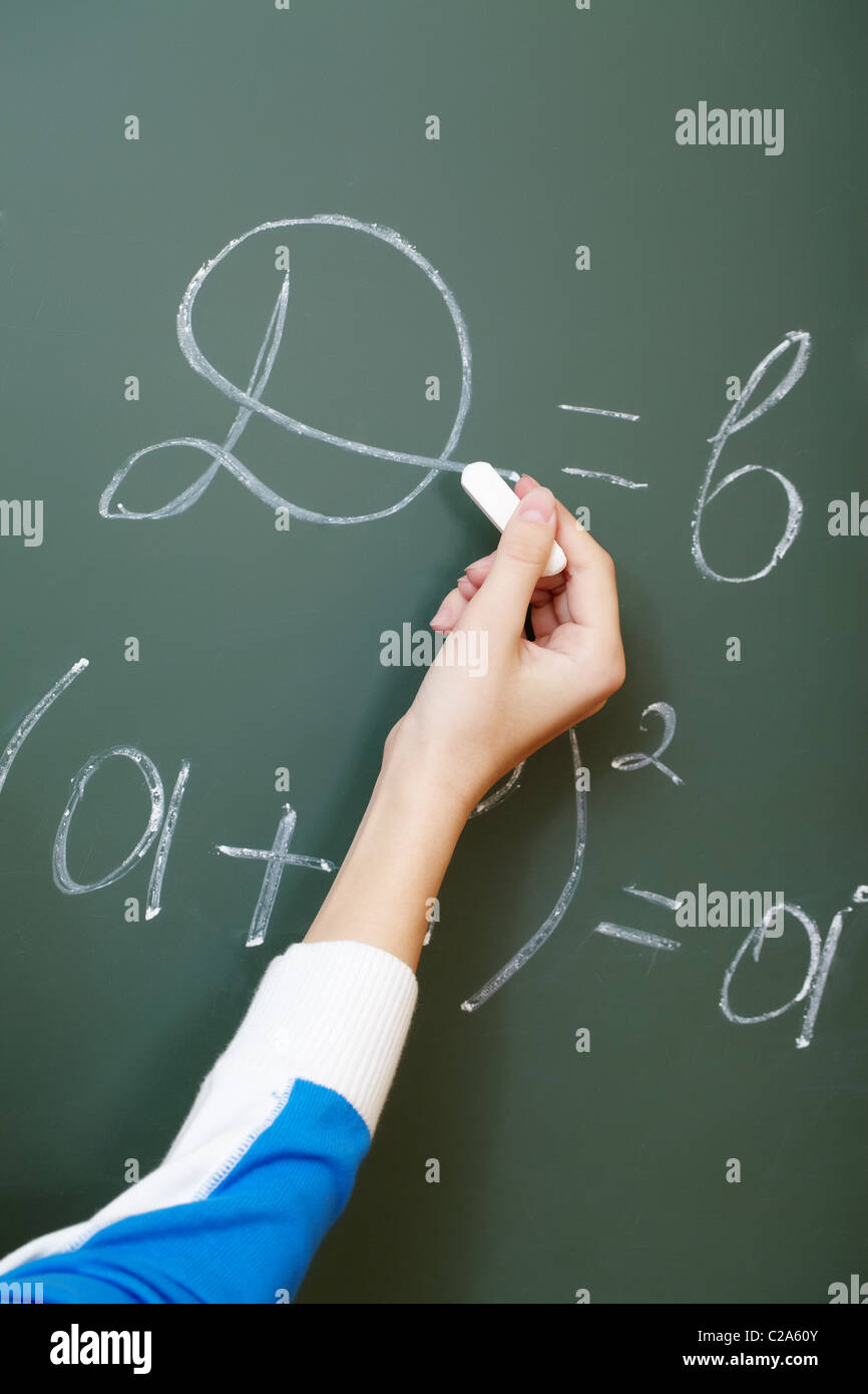 Hand of student writing formula on blackboard during algebra lesson ...