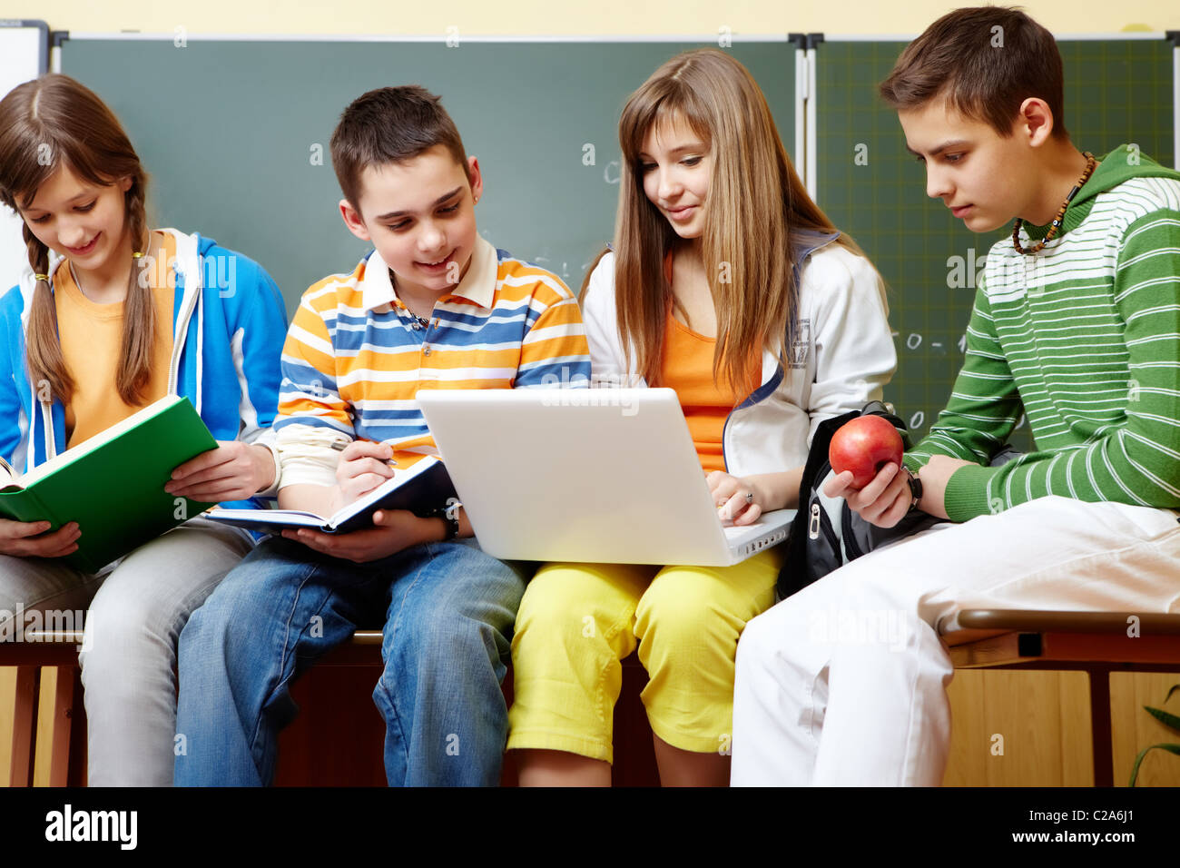 Portrait of clever students sitting in classroom and doing schoolwork ...