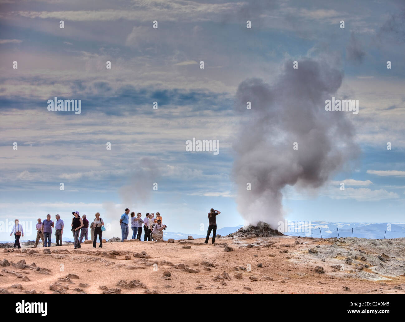 Tourist photographing steaming geyser in the geothermal field ...