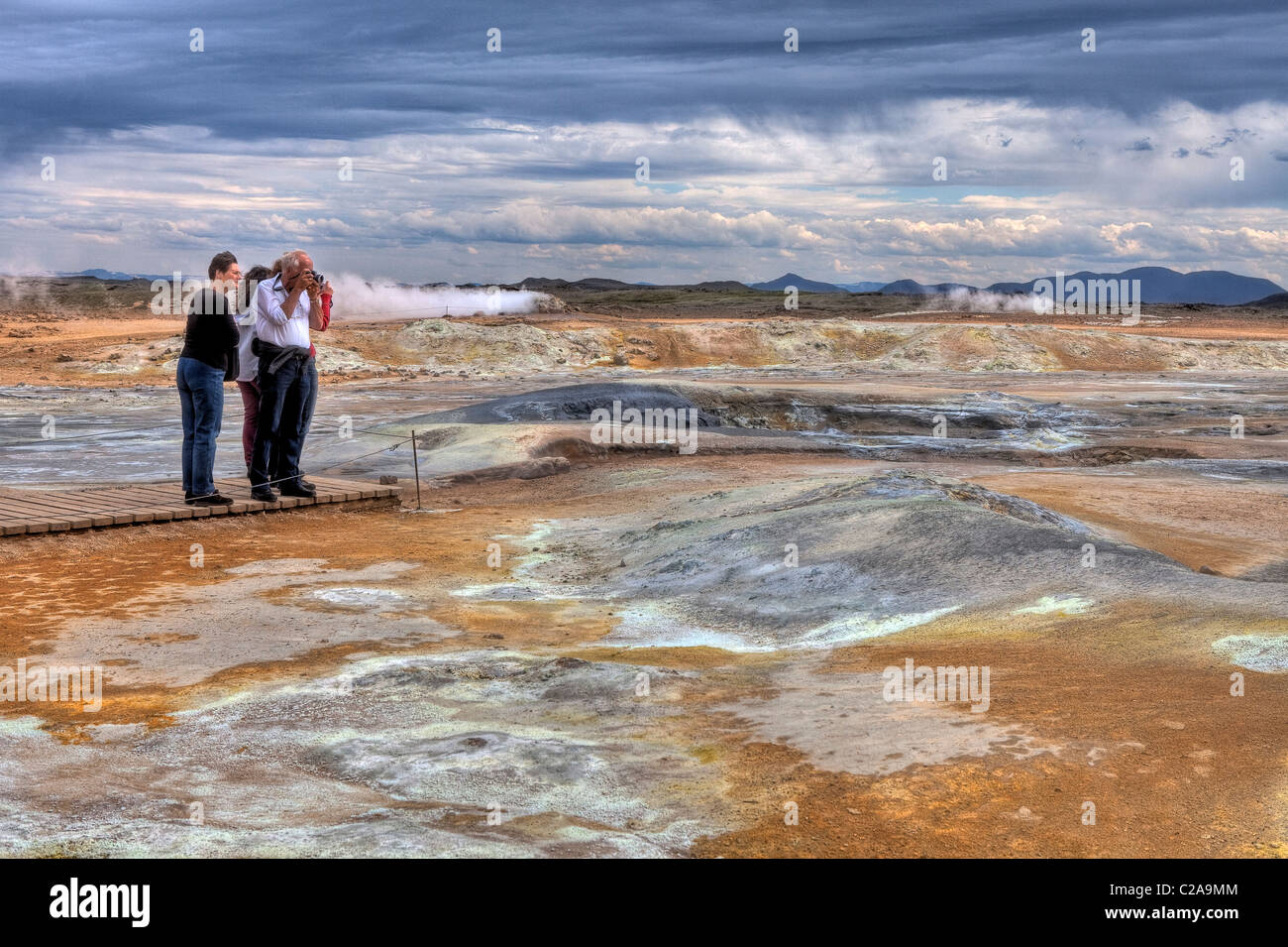Tourist photographing boiling mud pot in the geothermal field ...