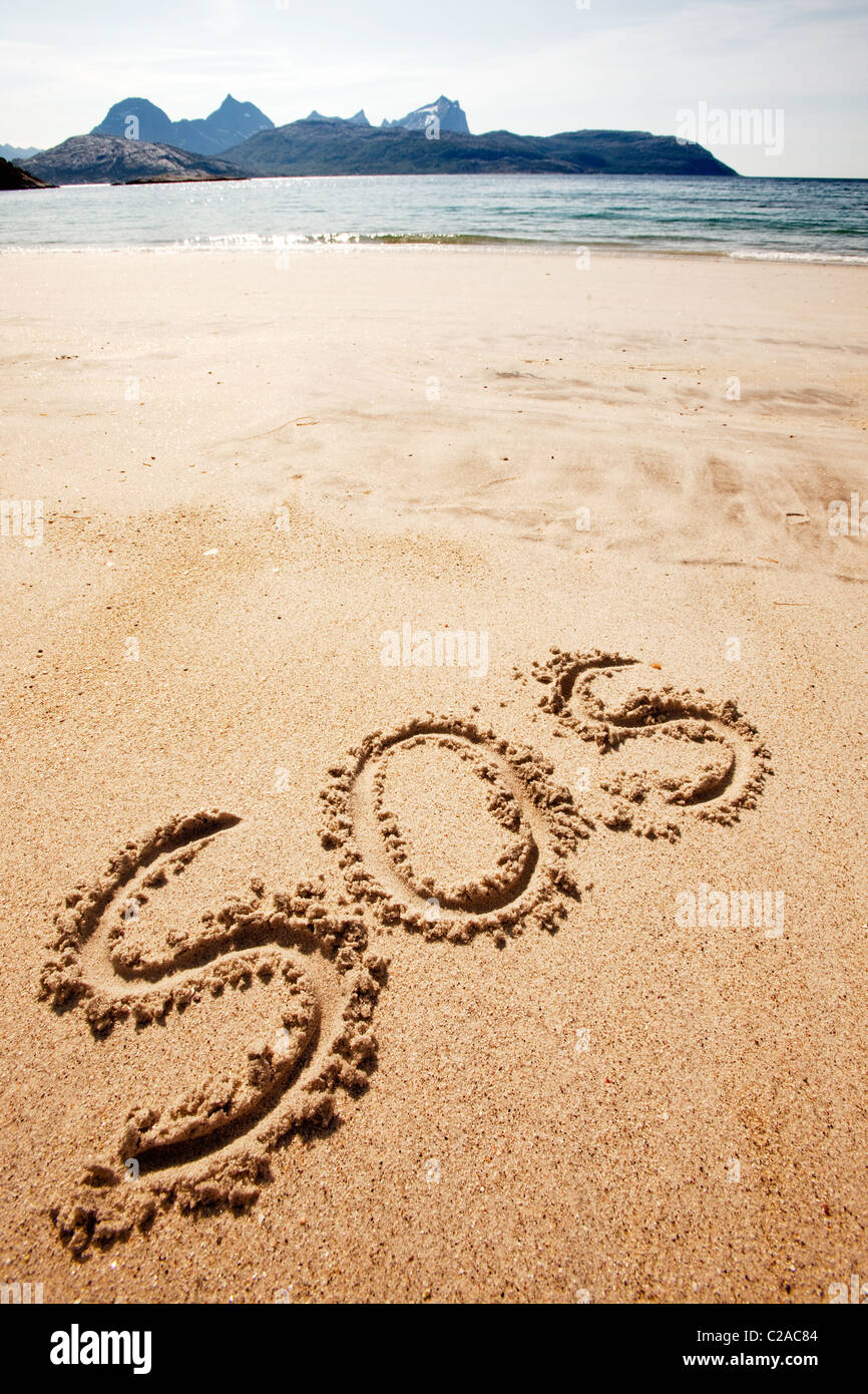 S.O.S written in the sand of an island with the ocean in the distance ...