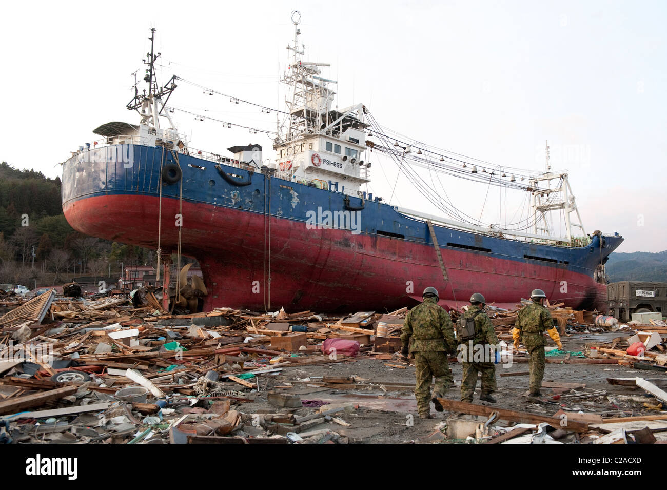 A massive ship pushed by the Tsunami inland sits while the JSDF ...
