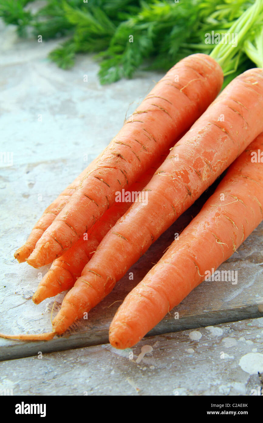 Fresh organic carrot with green leaves on an old table Stock Photo - Alamy