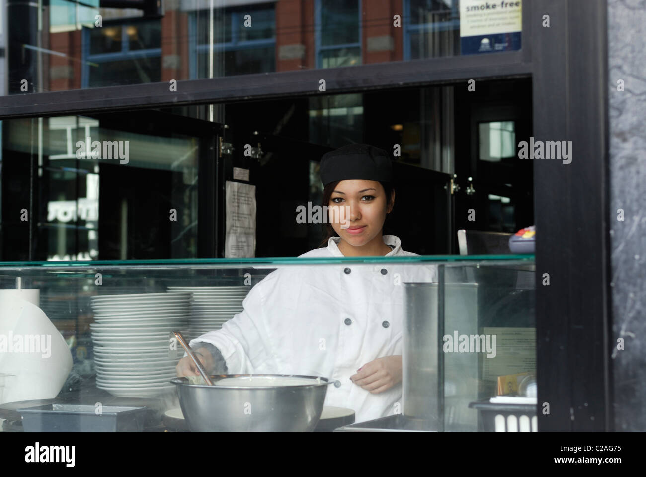 Beautiful young woman making crepes at a restaurant take out window ...