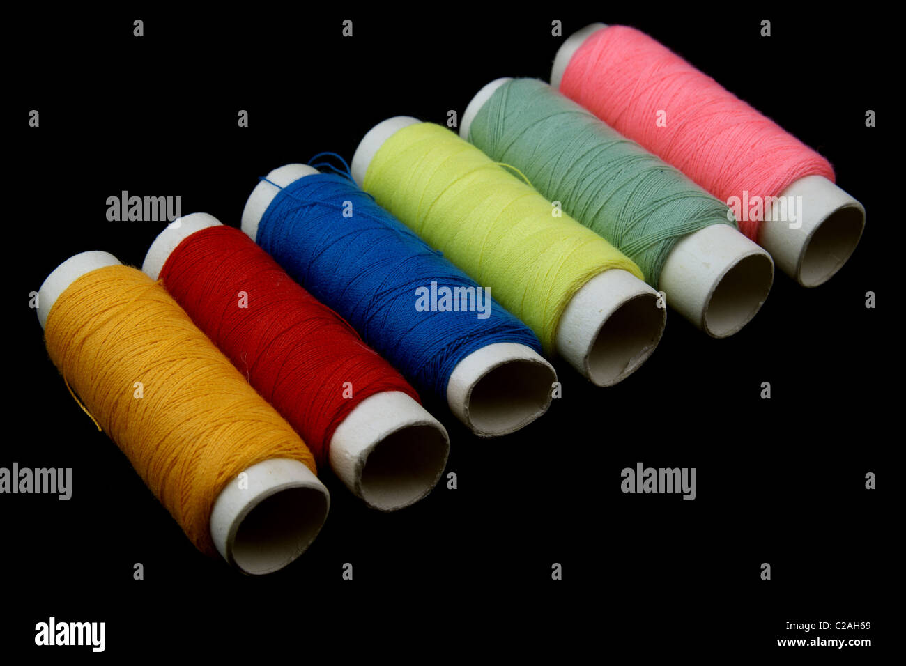 Colorful sewing threads on e black background Stock Photo - Alamy