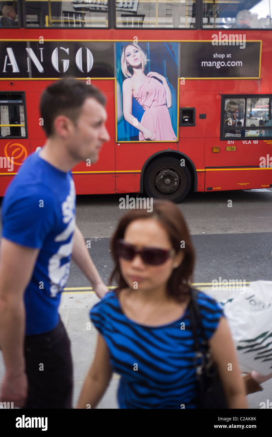 Passers-by and a red London bus advertising mango.com Stock Photo - Alamy