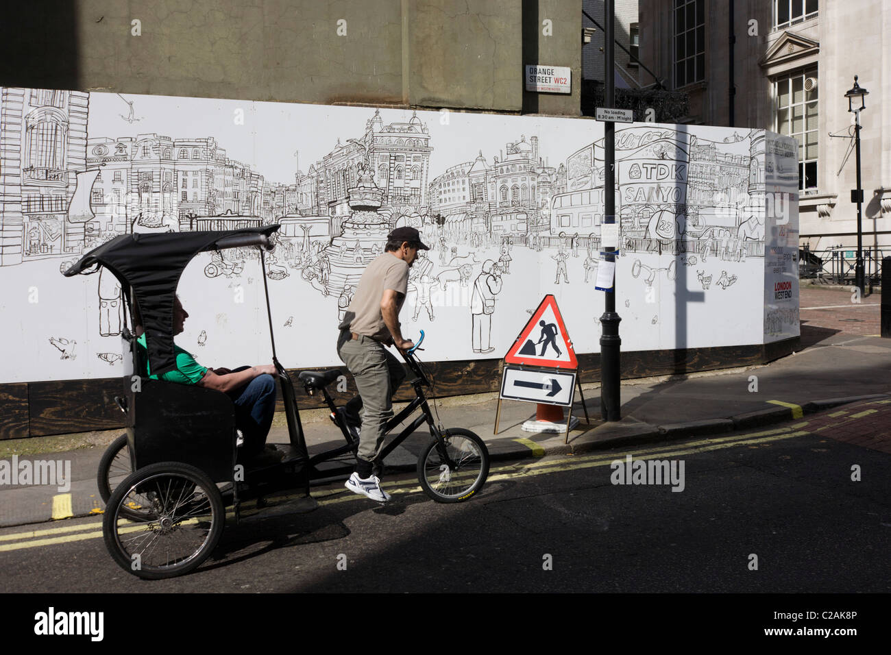 A passenger rides in a London pedal rickshaw bike through a side-street ...
