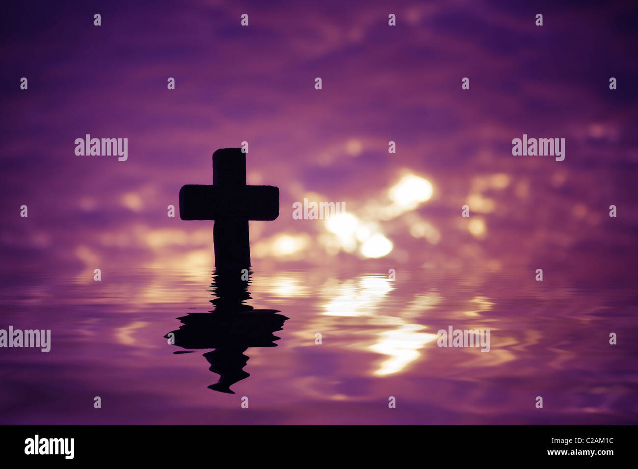 Silhouette of a Cross above the water with reflection in the sunset ...