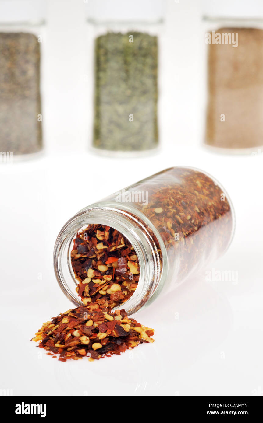 Bottle of the hot spice red pepper open and on it side with red pepper ...