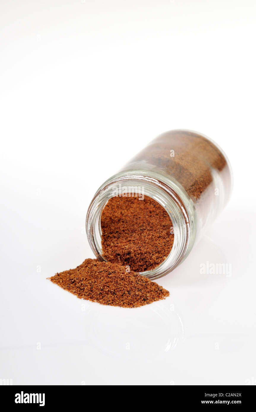 Bottle of the spice nutmeg open and on it side with nutmeg spilling out ...