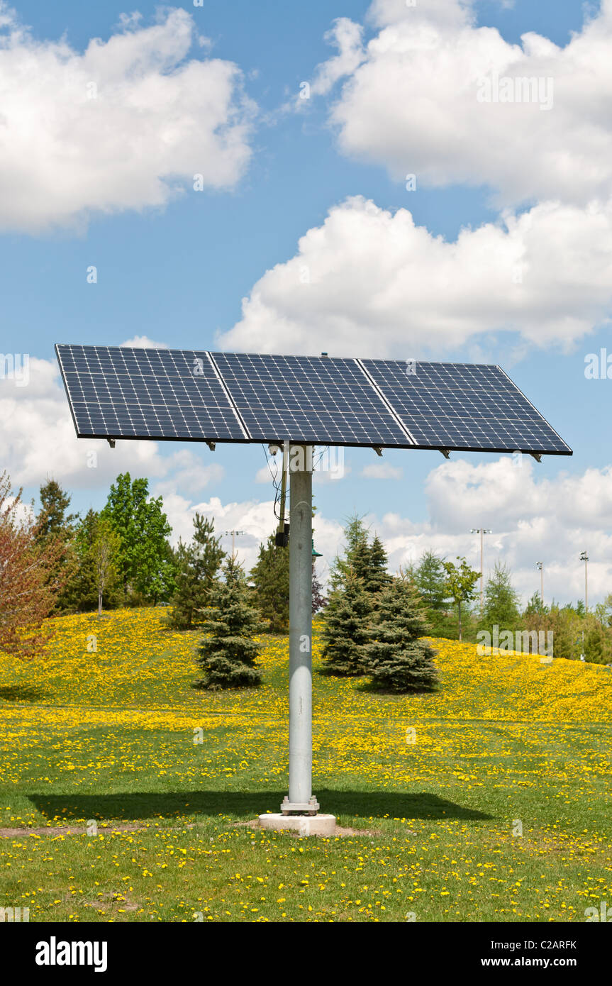 A photovoltaic solar panel array in a park with a blue sky and puffy ...
