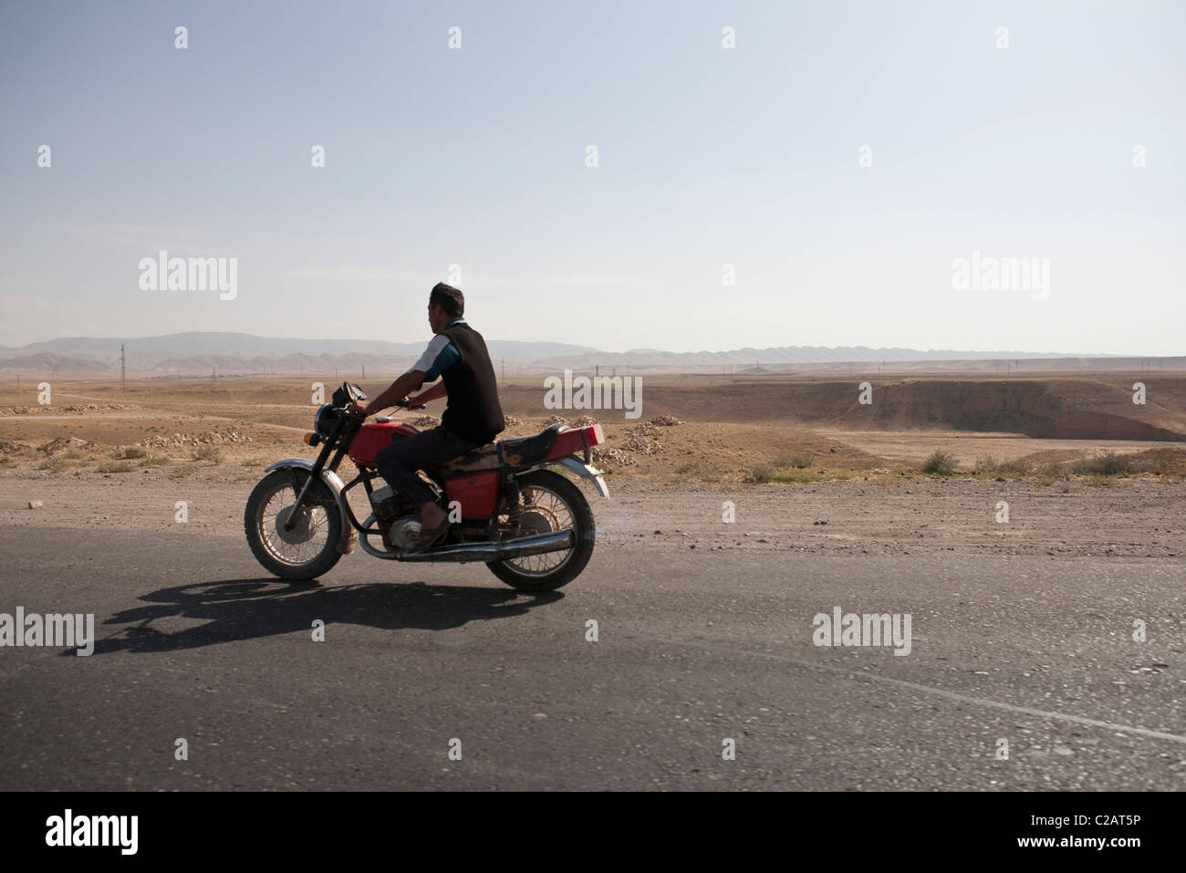 Uzbekistan, man riding on motorcycle along what used to be the Silk ...