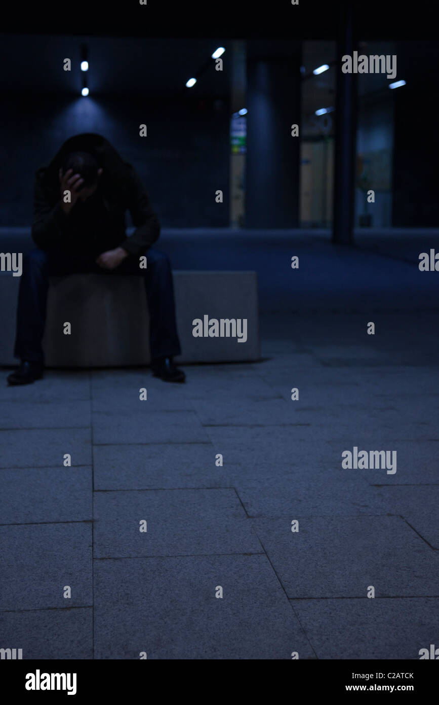 Man sitting outside at night with head in hands Stock Photo - Alamy