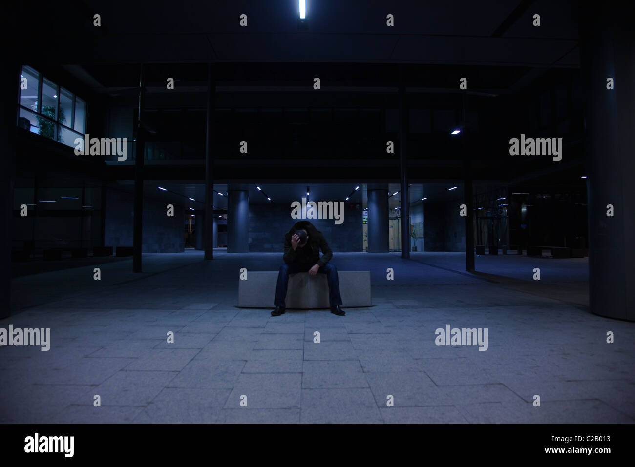 Man sitting outside at night with head in hands Stock Photo - Alamy