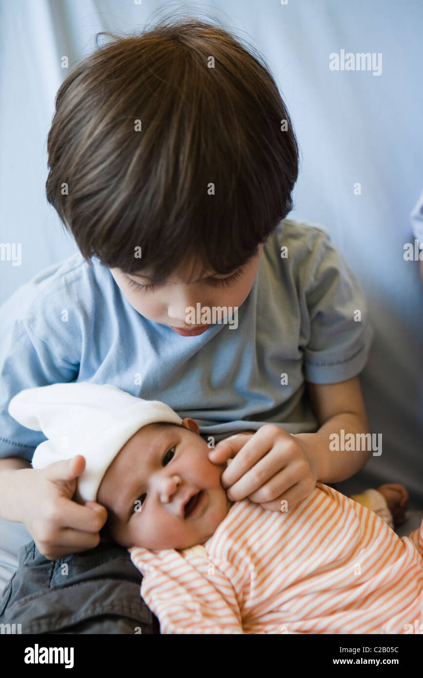 Young boy touching baby sibling's cheek Stock Photo - Alamy