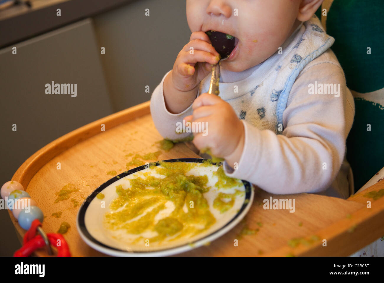 Baby girl chewing on spoon Stock Photo - Alamy