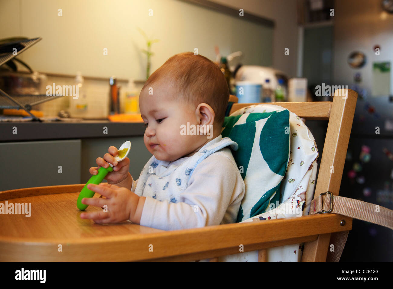 Baby girl eating, playing with spoon Stock Photo - Alamy