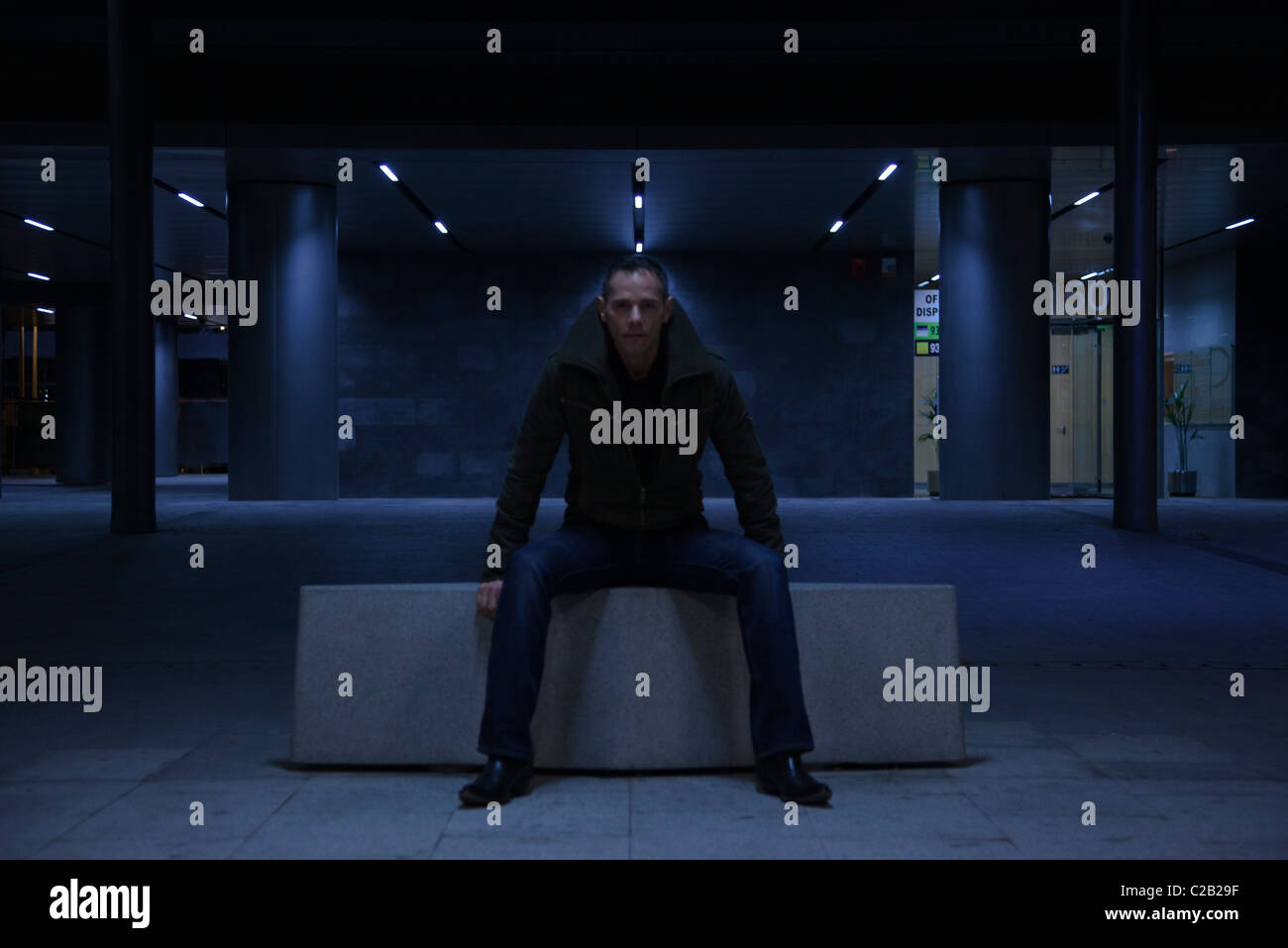 Man sitting outside of modern building at night, portrait Stock Photo ...