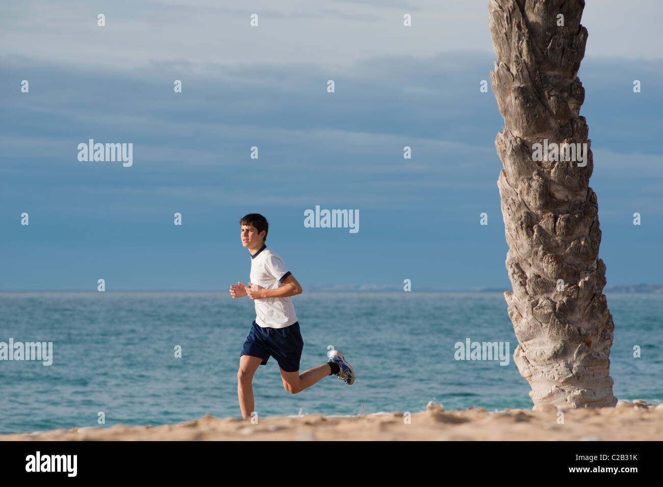 Fit teenager jogging early morning on the beach Stock Photo - Alamy