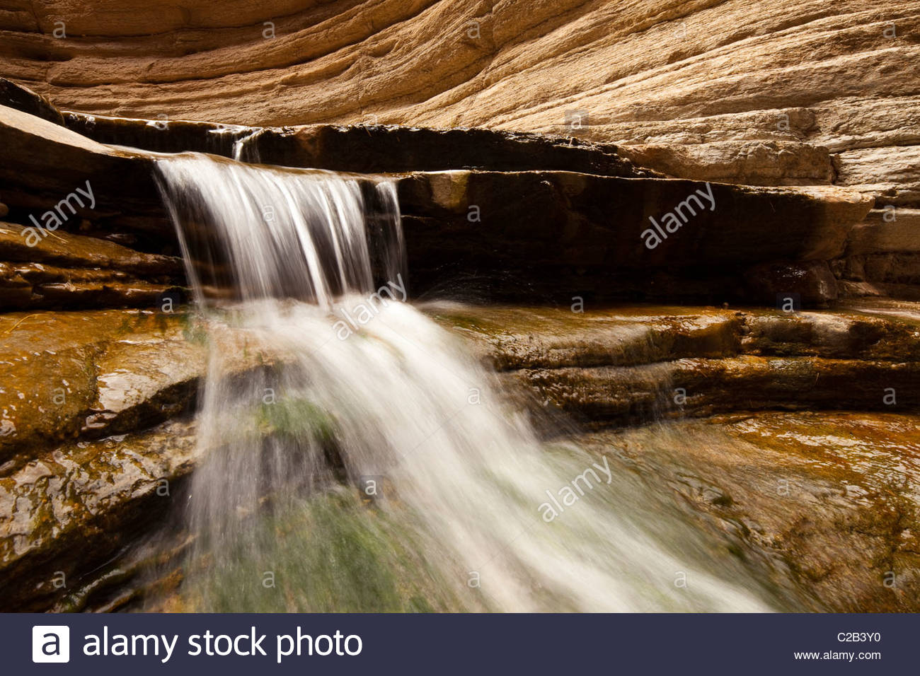 A waterfall flows over layers of desert rock Stock Photo - Alamy