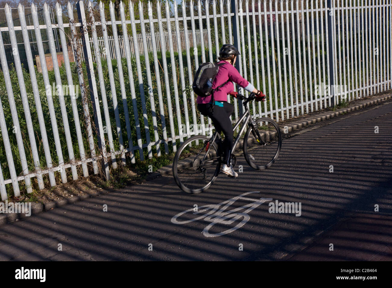 A commuting cyclist rides alongside sunlit railings on a backroad in ...