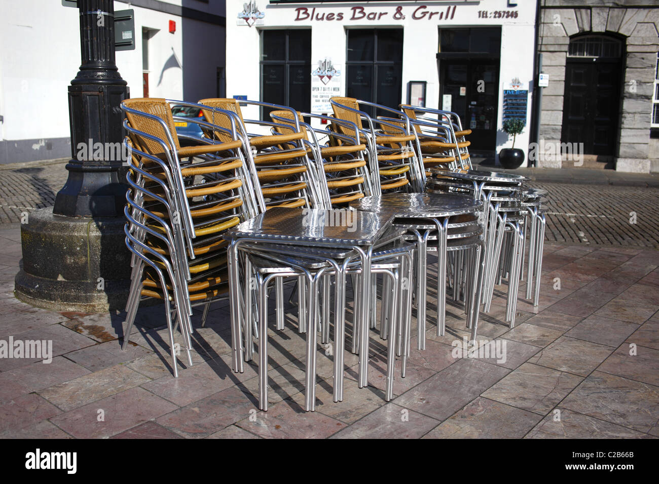 Stacked steel tables and chairs outside a restaurant Stock Photo - Alamy
