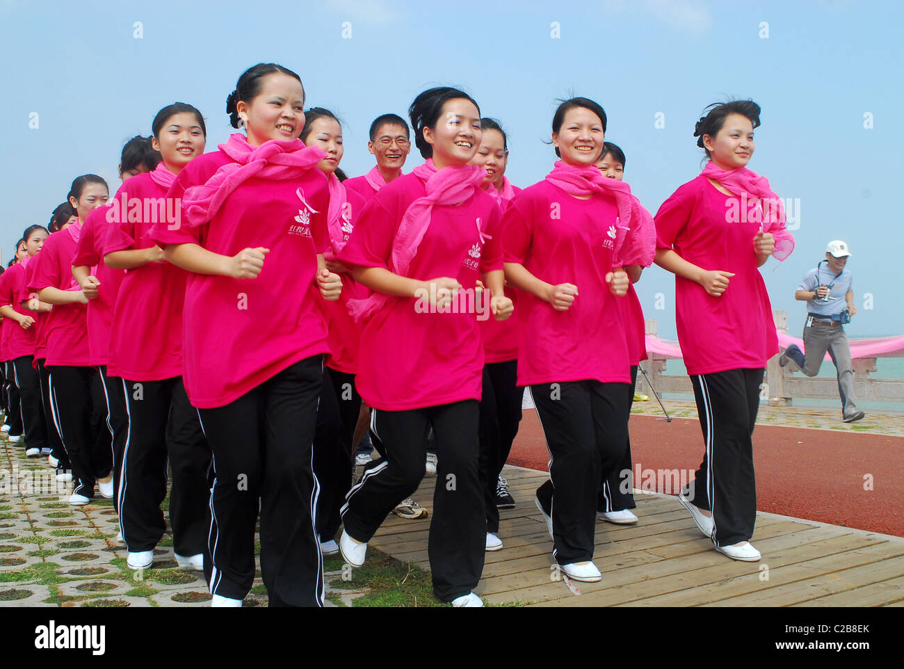 Female volunteers with red ribbons take part in a long-distance running ...