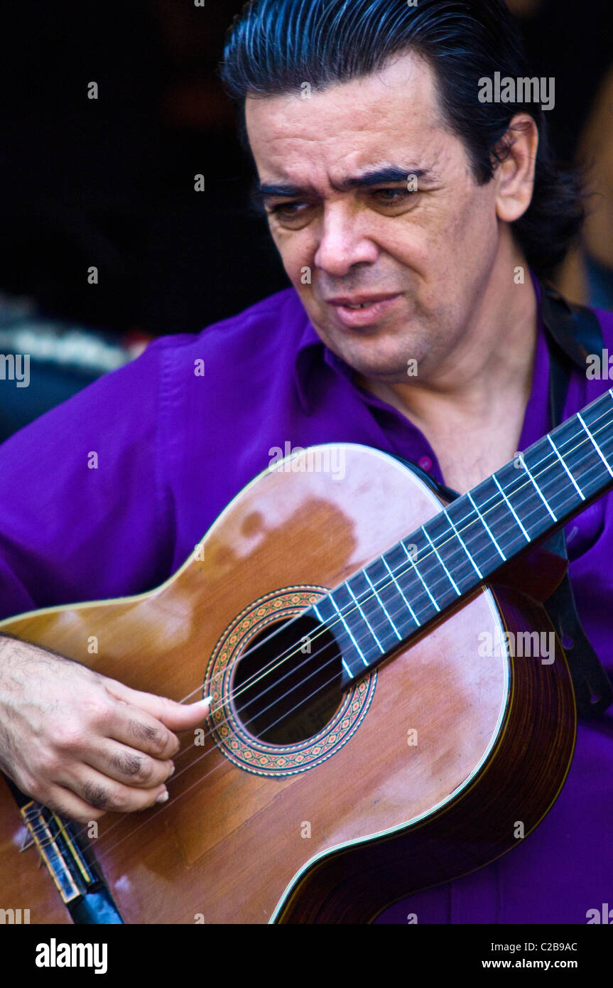 A musician strums an acoustic guitar creating rhythm for Tango dancers ...