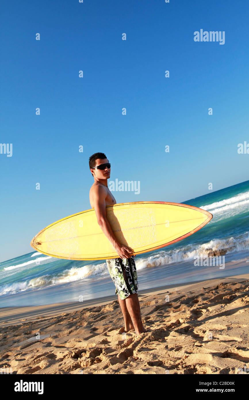 Surfer holding a surfboard on tropical beach Stock Photo - Alamy