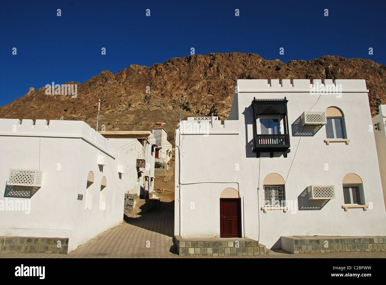 Oman, Muscat, exterior of buildings with mountain in the background ...