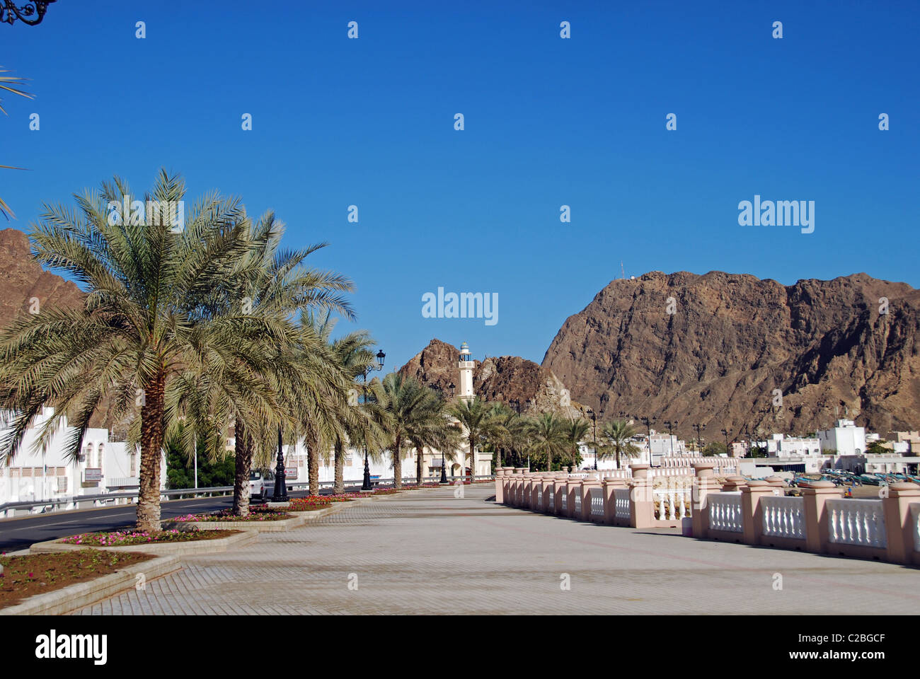 Oman, Muscat, view of treelined by pathway with mosque and mountain in ...