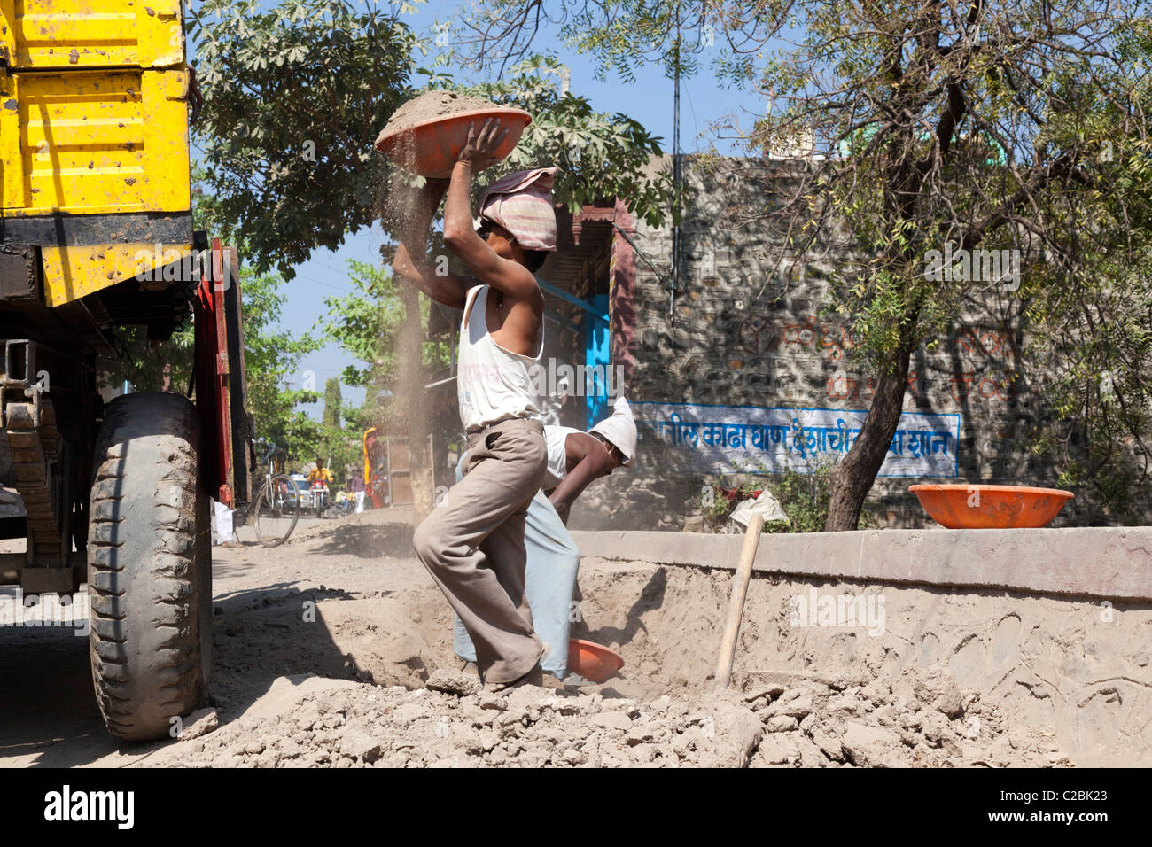 Indian male laborers repairing a road in the village of Valsang ...