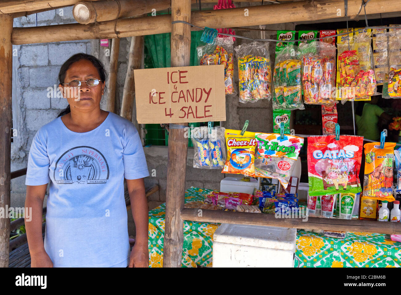 A female Filipino shop keeper standing by her stall with goods for sale ...