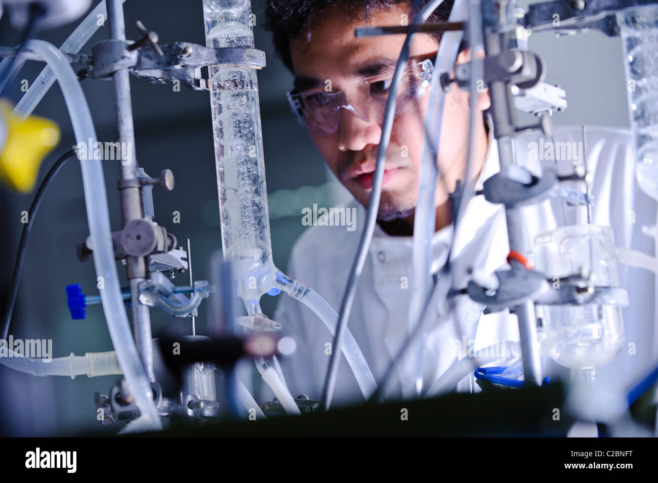 Young Asian male scientist wearing clear goggles and white science coat ...