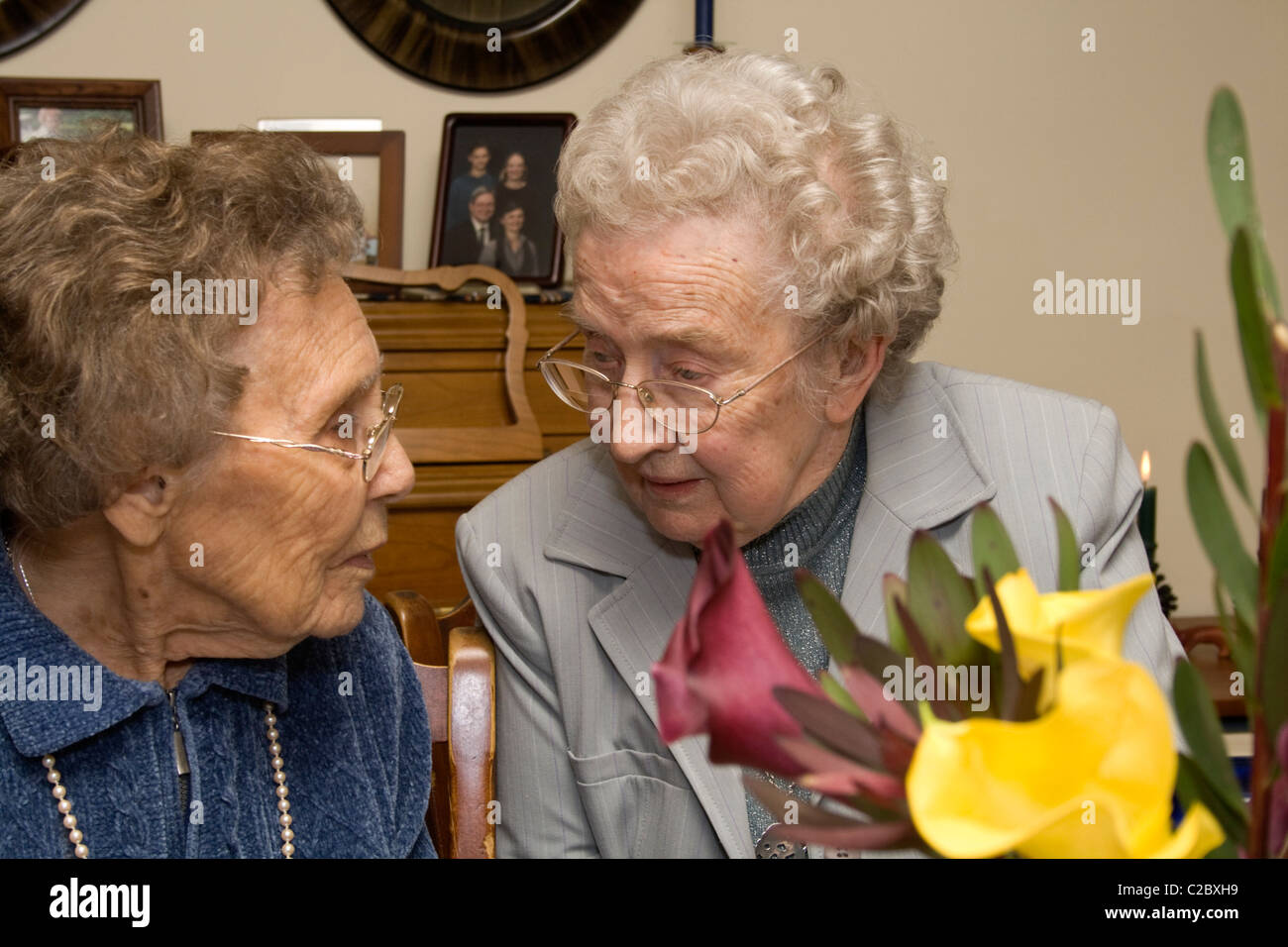 Two women ages 100 and 90 in deep conversation at family dinner party ...