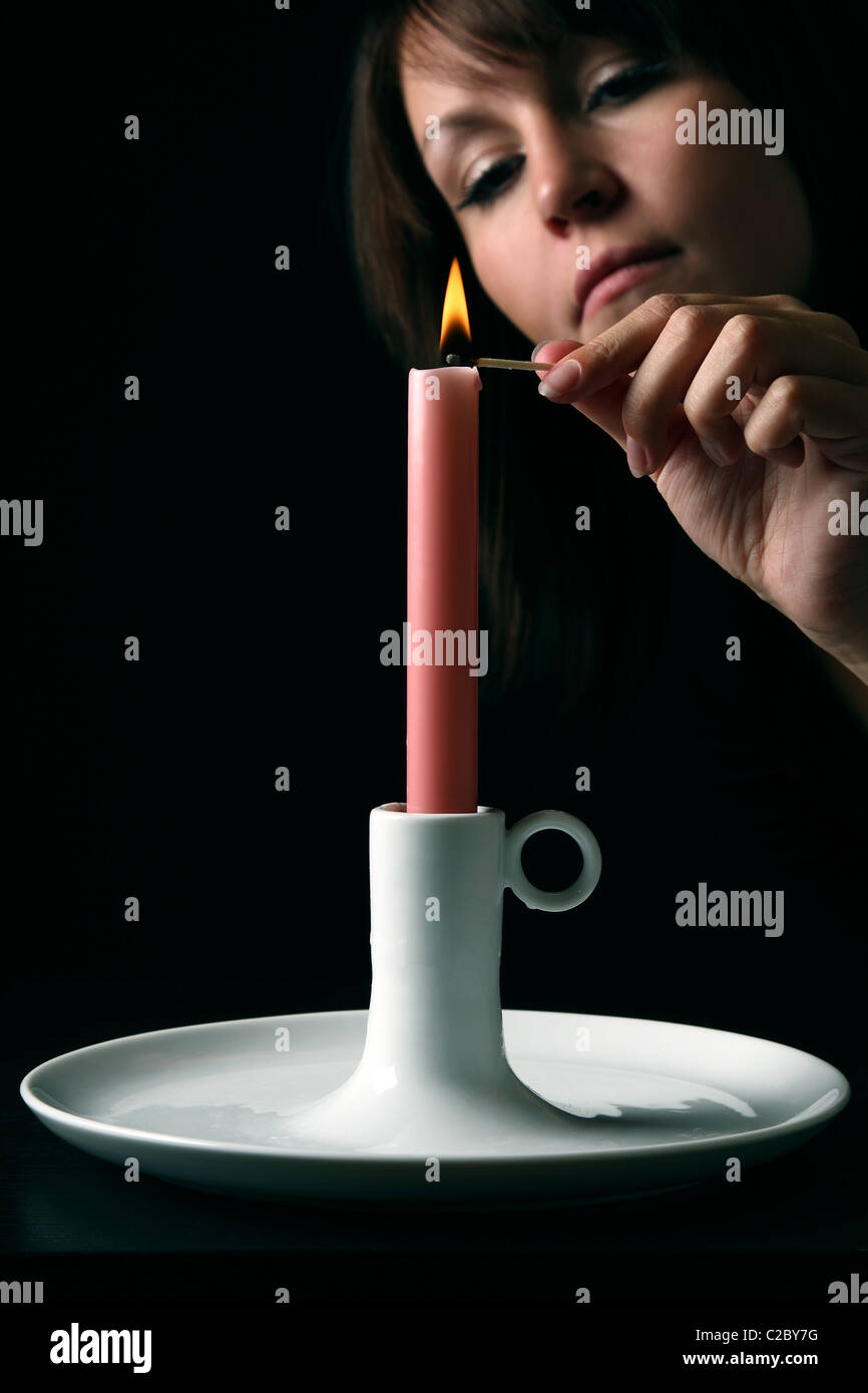 A young woman lighting a candle Stock Photo - Alamy