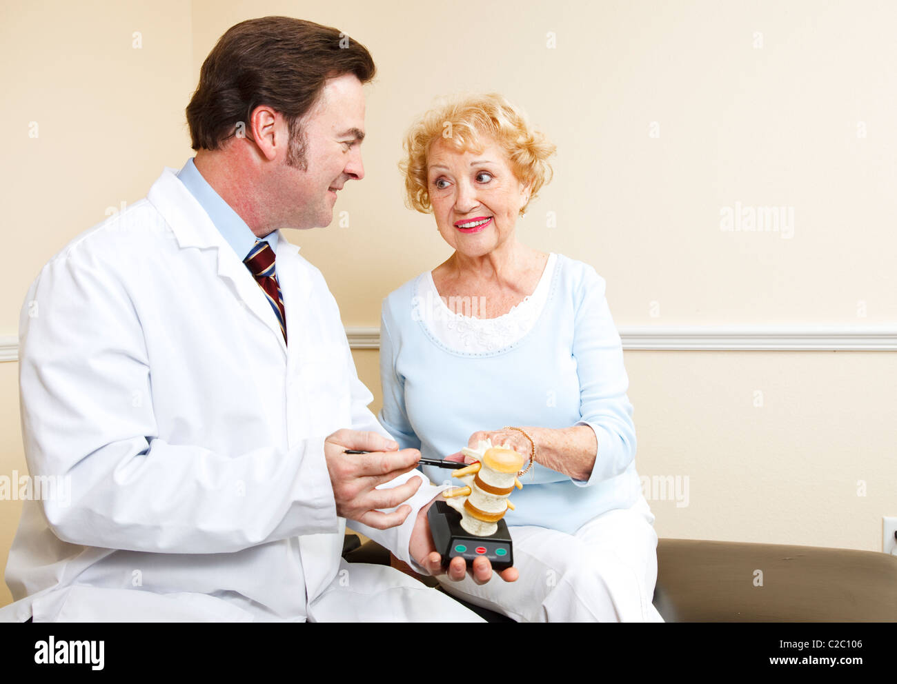 Chiropractor uses a model of the human spine to explain treatment to a ...