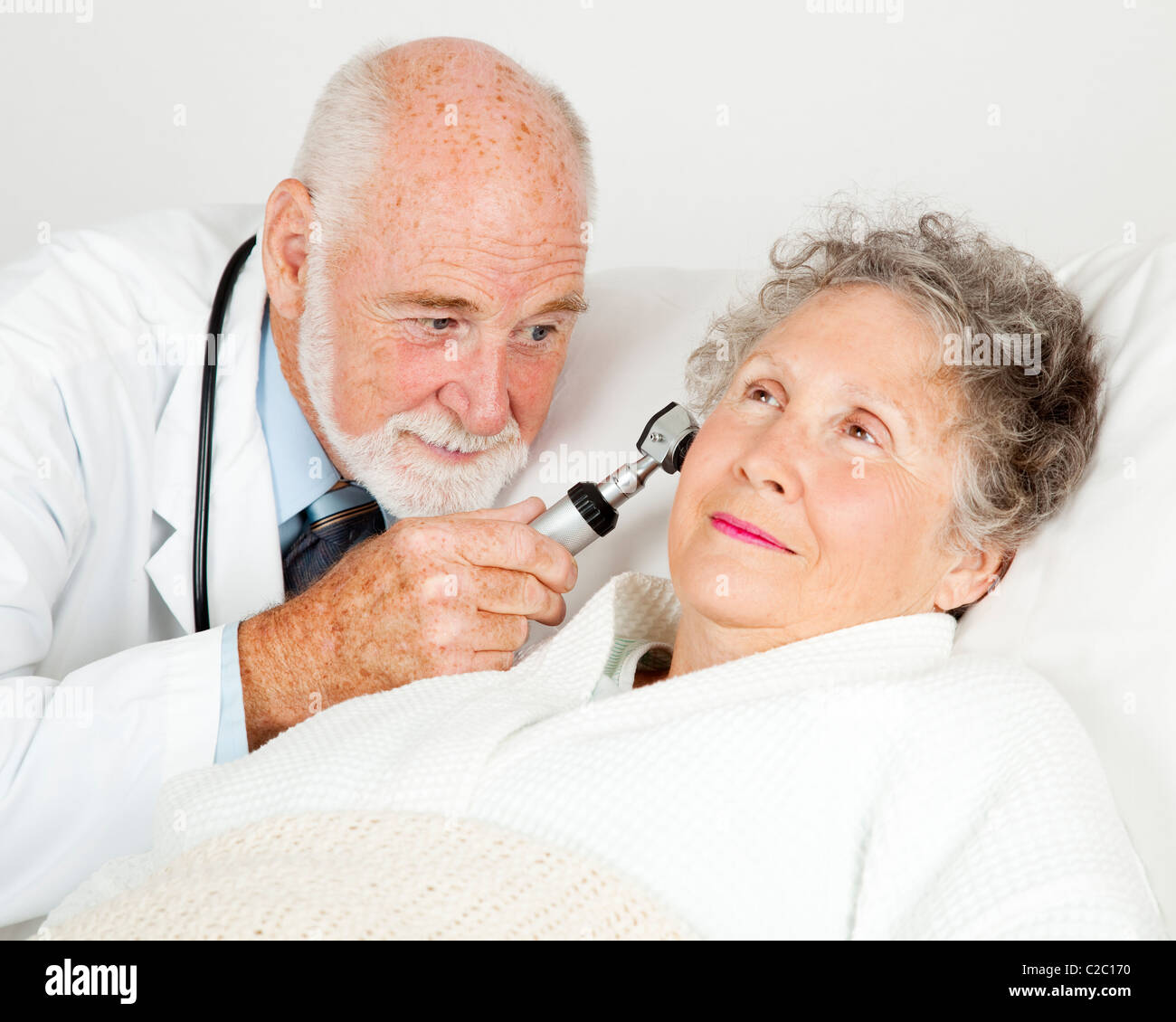 Doctor using an otoscope to examine a hospital patient's ear canal ...