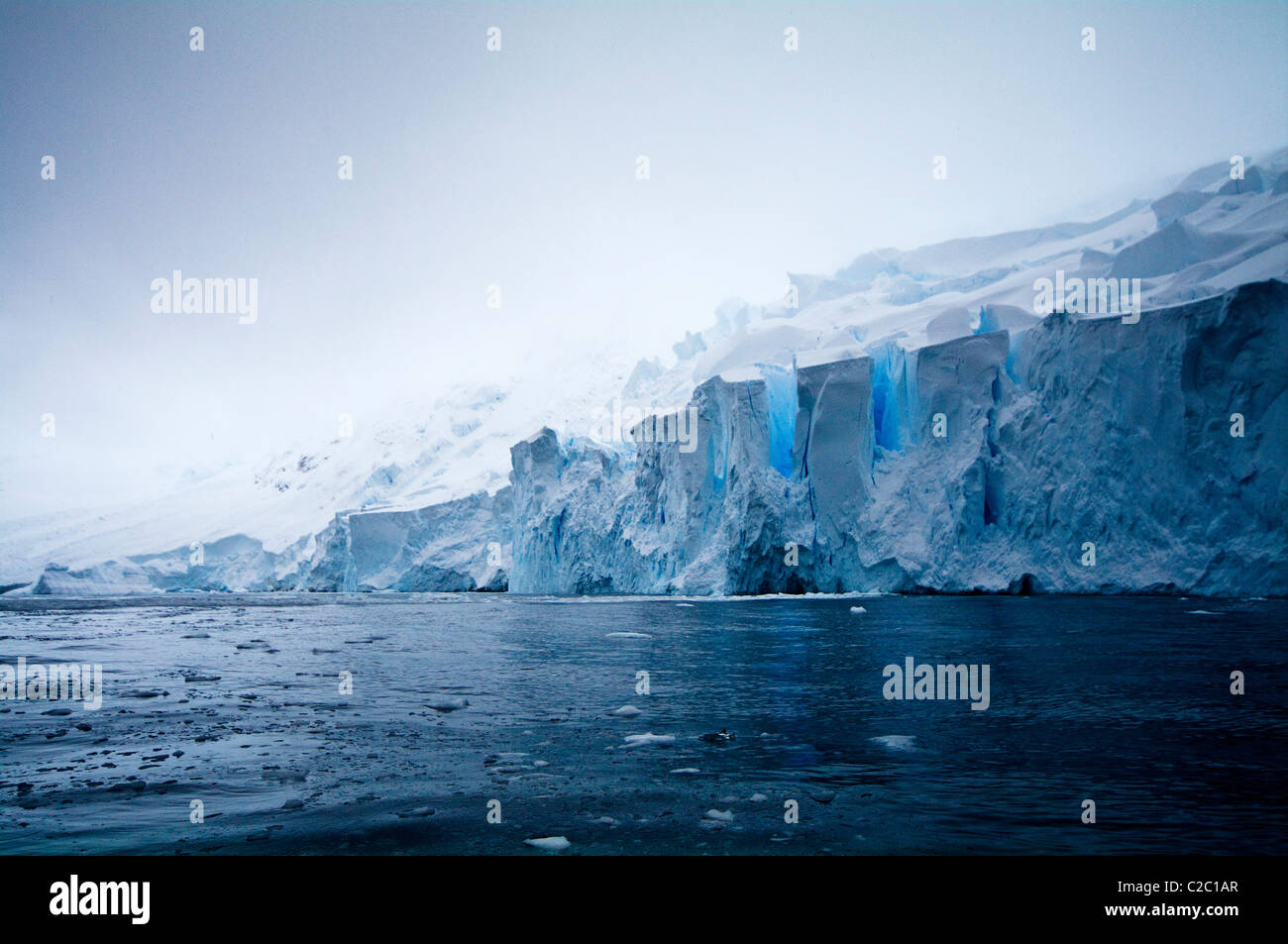 The fracture zone of massive glacial ice cliffs teeter over icy seas ...