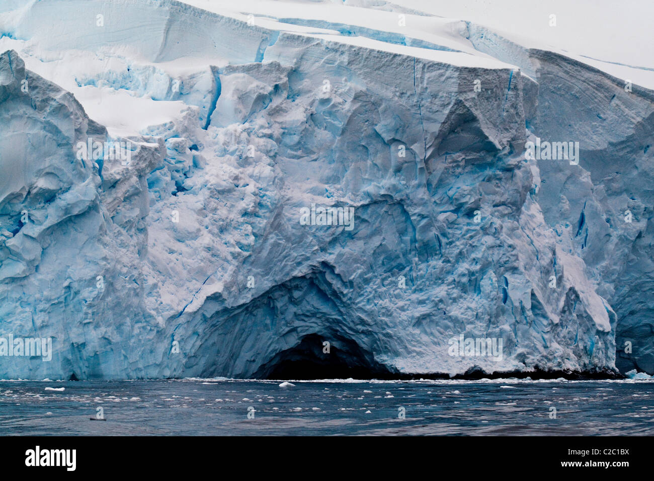 Melting ice water erodes a cave and tunnel in a glacial ice cliff Stock ...