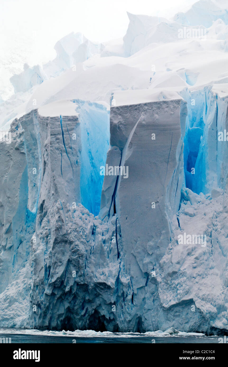The fracture zone of massive glacial ice cliffs teeter over icy seas ...