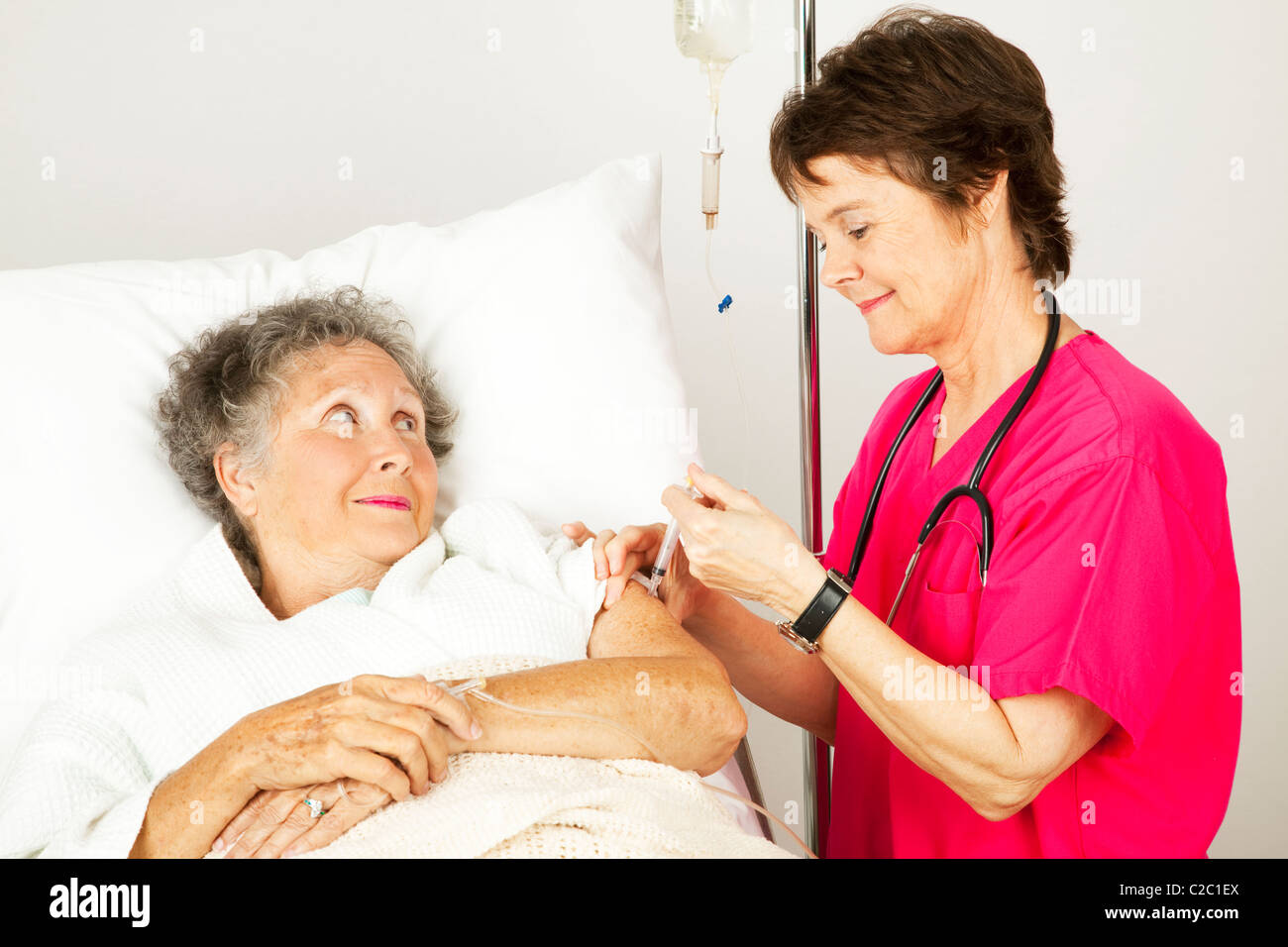Hospital nurse giving an elderly female patient an injection in her arm ...