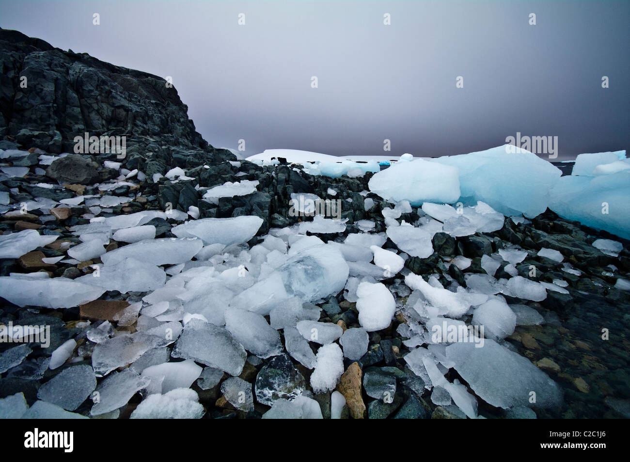 Ice boulders strewn over a rugged, stormy diorite beach and shoreline ...