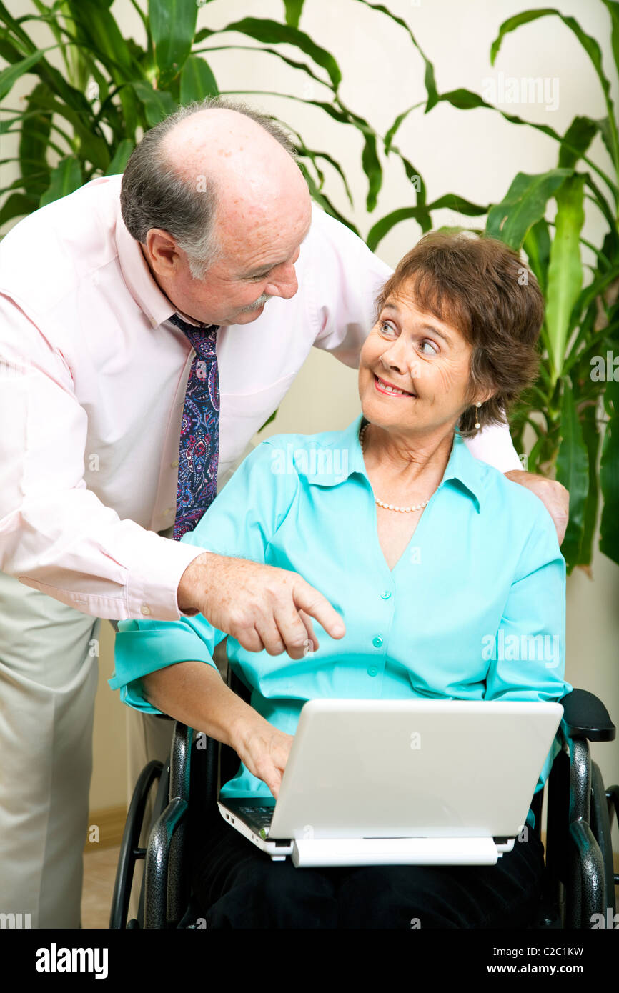 Secretary in wheelchair, typing on her laptop computer while her boss ...