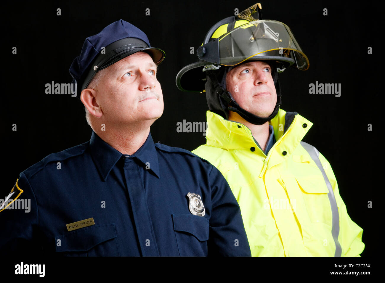 Reverent looking policeman and fireman photographed in front of a black ...